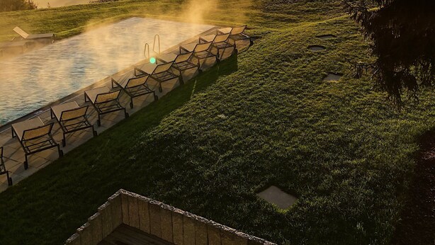 Paisagem tranquila com piscina, caminho de pedra e vegetação exuberante.