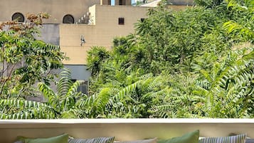 Terraço no telhado com área de estar, vegetação exuberante e vista para um edifício com torre.