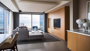 Uma sala de estar moderna com uma janela grande, um sofá, uma mesa de centro e uma televisão.