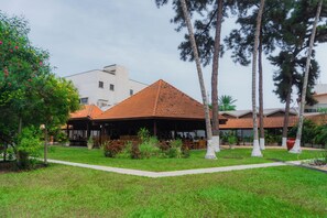 Um edifício com telhado de cerâmica, cercado por uma área gramada com árvores e um caminho.