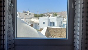 Janela com vista para uma área residencial, incluindo edifícios e céu claro.