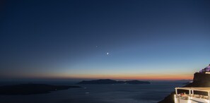 Vista costeira ao entardecer, com um restaurante em um penhasco com vista para o mar.