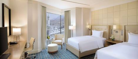 Quarto de hotel com duas camas, uma mesa de trabalho com televisão, uma cadeira e vista para a cidade.