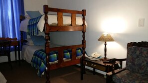 Quarto com beliche, escrivaninha com luminária, cadeira e telefone.