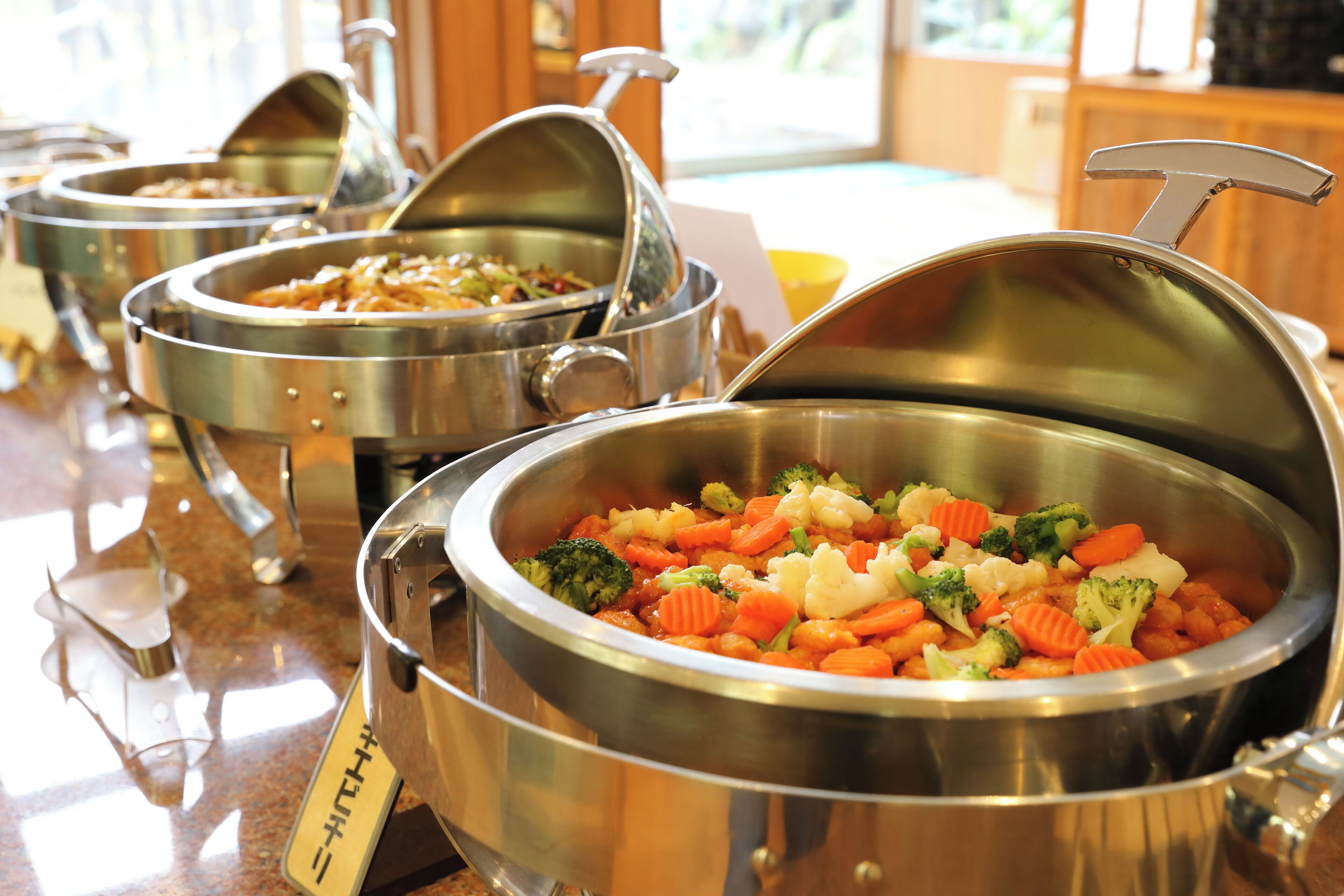 Buffet com diversos pratos, incluindo uma tigela de legumes variados.