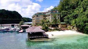 Resort com praia, águas cristalinas e montanhas ao fundo.
