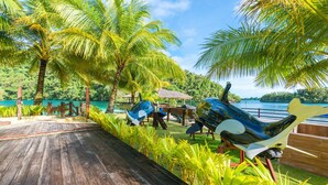 Um deck de madeira com cadeiras de lounge e uma grande escultura decorativa de peixe.