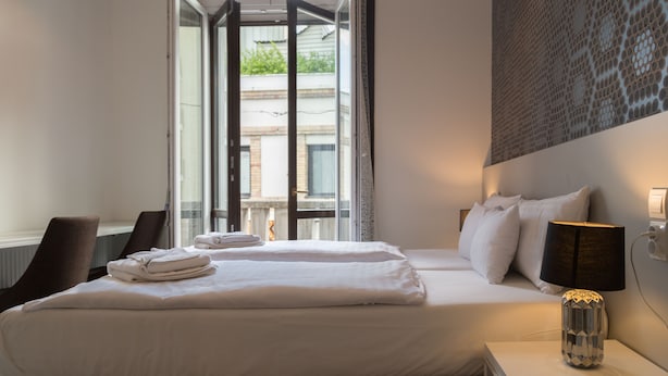 Quarto de hotel com uma cama grande, uma escrivaninha e vista através de uma porta aberta.