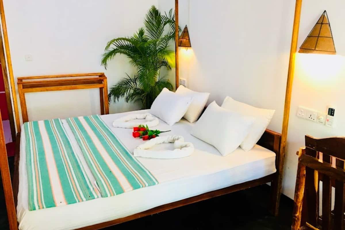 Uma cama de solteiro com colcha listrada, almofadas brancas e um pequeno buquê de flores.