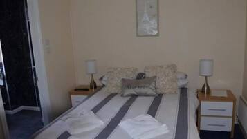 Quarto de hotel com cama, duas mesas de cabeceira, duas luminárias, um travesseiro e um quadro na parede.