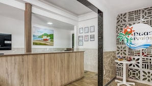 Uma área de recepção com balcão de madeira, certificados emoldurados na parede e um painel decorativo com um logotipo.