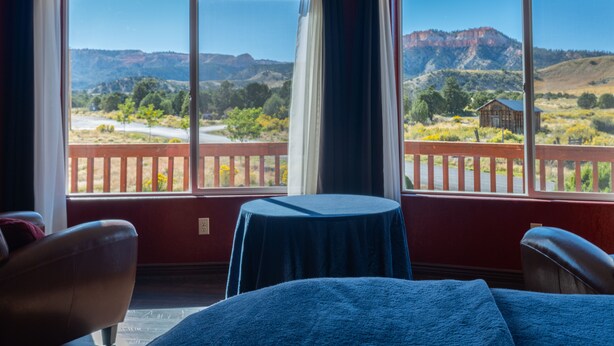 Quarto com uma janela grande que oferece vista para uma paisagem montanhosa.