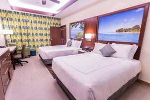Quarto de hotel com duas camas, uma escrivaninha e uma cadeira.