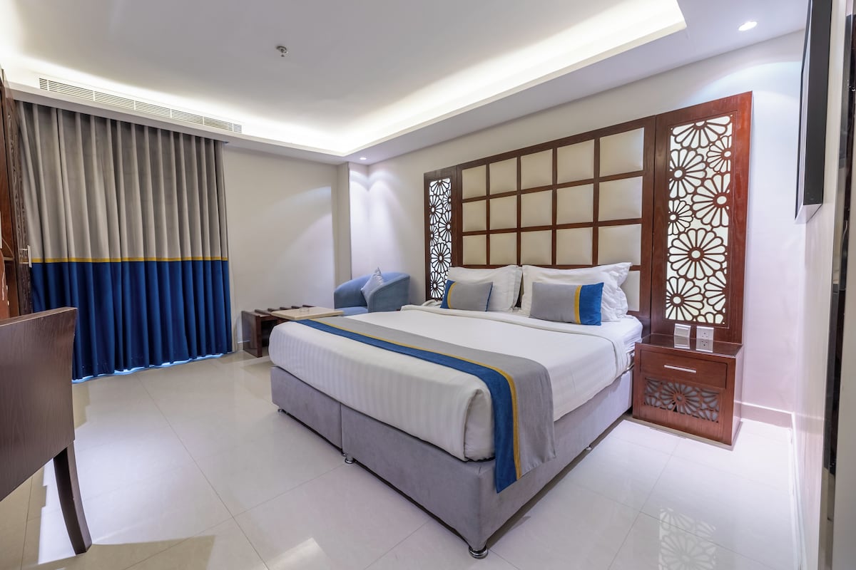 Quarto de hotel com uma cama grande, uma escrivaninha e um painel decorativo.