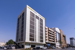 Um edifício de vários andares com uma placa que indica 'Serviced Apartments' e um céu limpo acima.