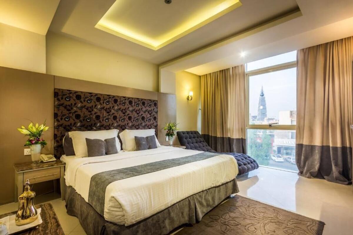 Quarto de hotel moderno com uma cama grande, vista para a cidade e cabeceira decorativa.