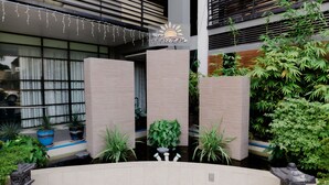 Um hotel moderno com um jardim central, plantas em vasos e uma placa com a inscrição 'The Horizon'.