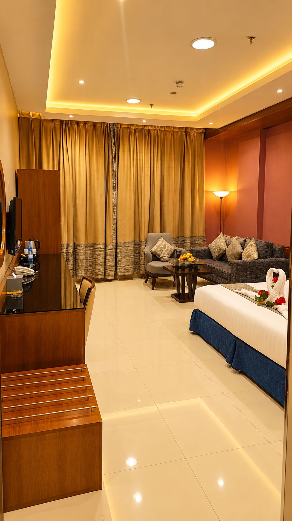Quarto de hotel com cama, escrivaninha, sofá e abajur.