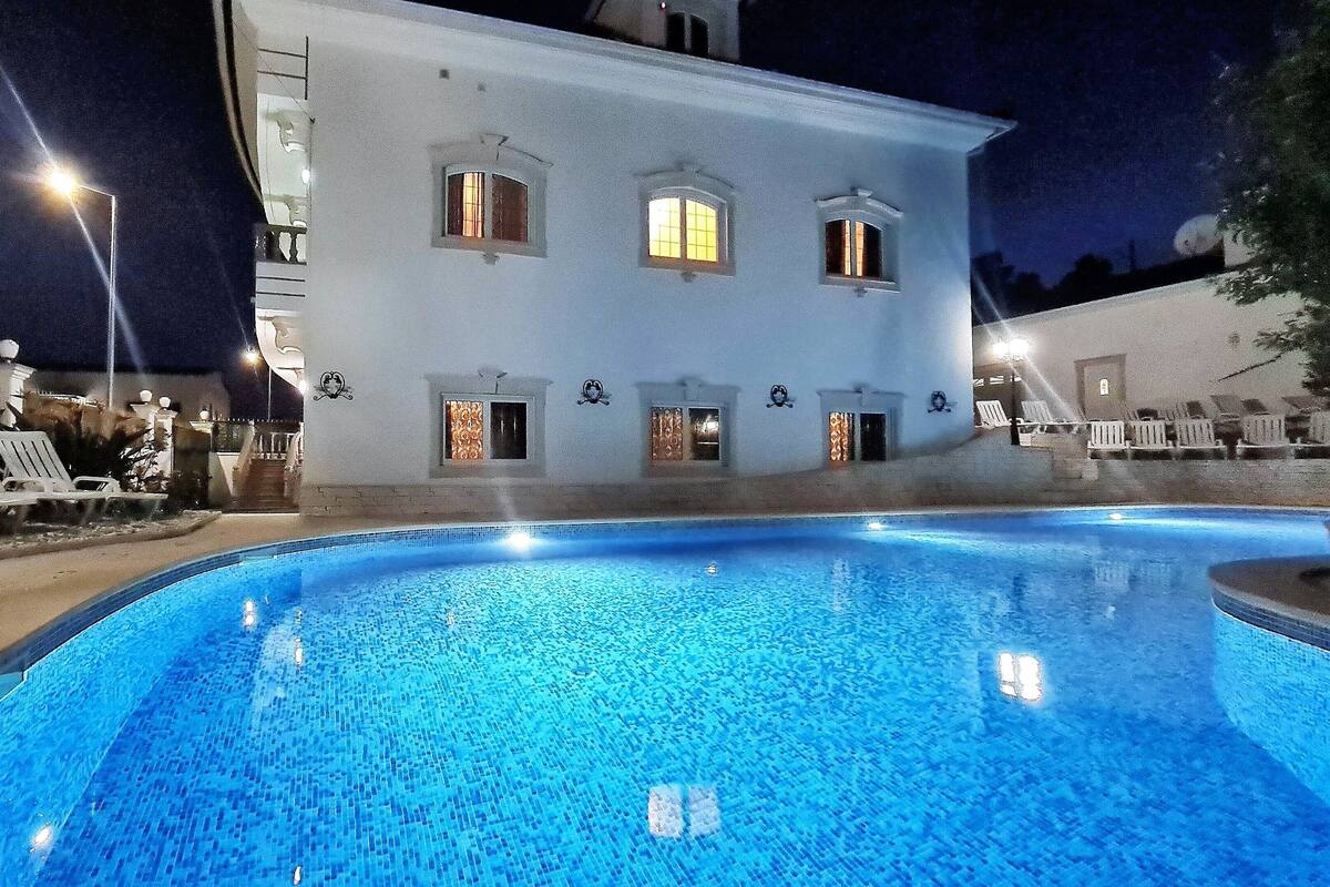 Piscina com um edifício branco ao fundo.