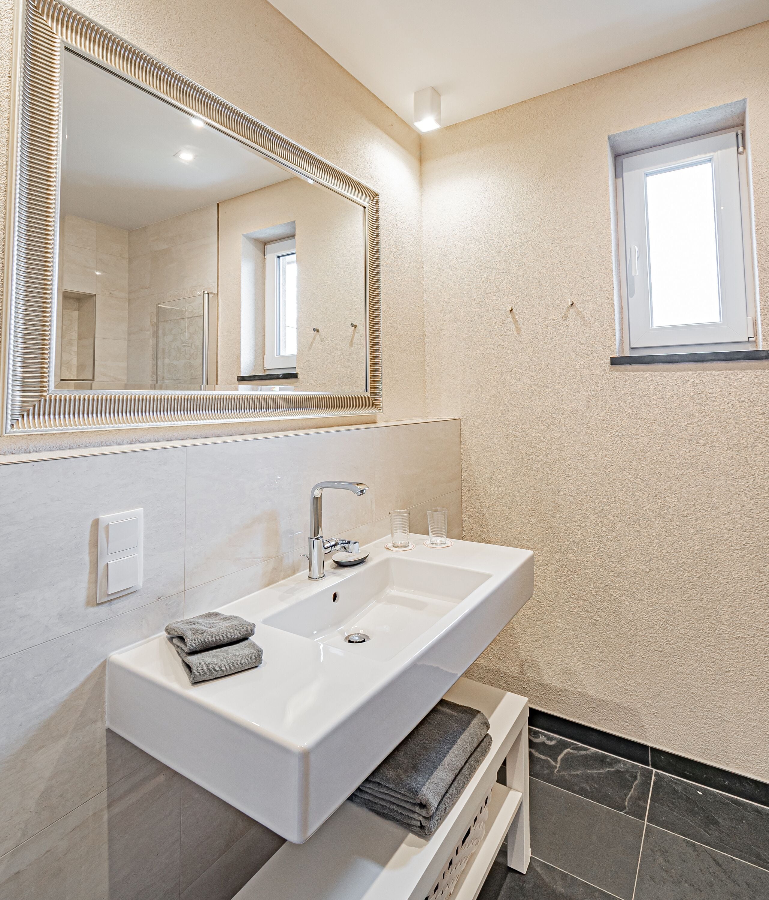 Uma casa de banho moderna com um espelho grande, duas pias e uma janela.