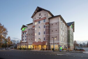 Um hotel Holiday Inn Express de vários andares, com fachada de tijolos, várias janelas e entrada bem iluminada.