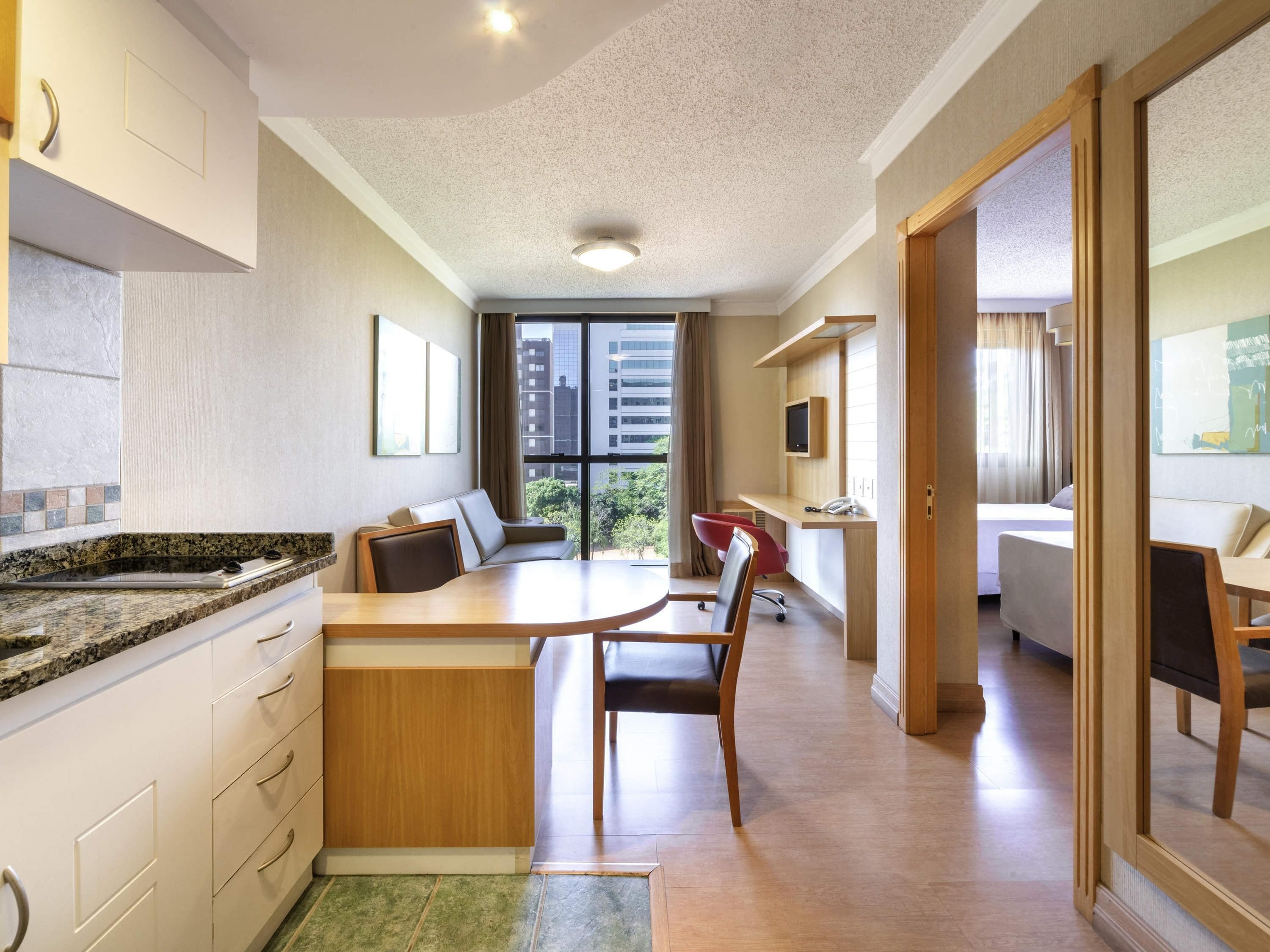 Quarto de hotel moderno com cozinha, mesa de jantar, sofá e cama.