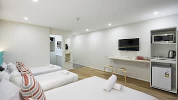 Quarto de hotel com duas camas, televisão, micro-ondas, frigorífico e uma pequena área de estar.