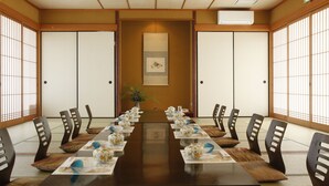 Uma sala de conferências com uma mesa comprida, cadeiras e um vaso decorativo.
