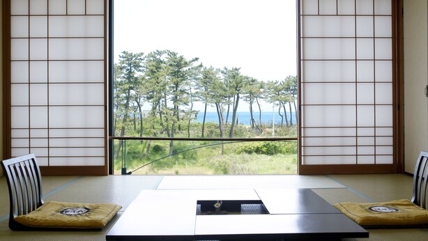 Um quarto japonês tradicional com tatames, uma mesa baixa e painéis shoji.