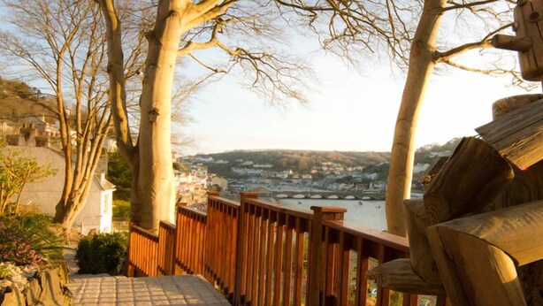 Um deck de madeira com vista para um rio e uma ponte ao longe.
