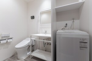 Uma casa de banho moderna com sanita, lavatório e chuveiro.