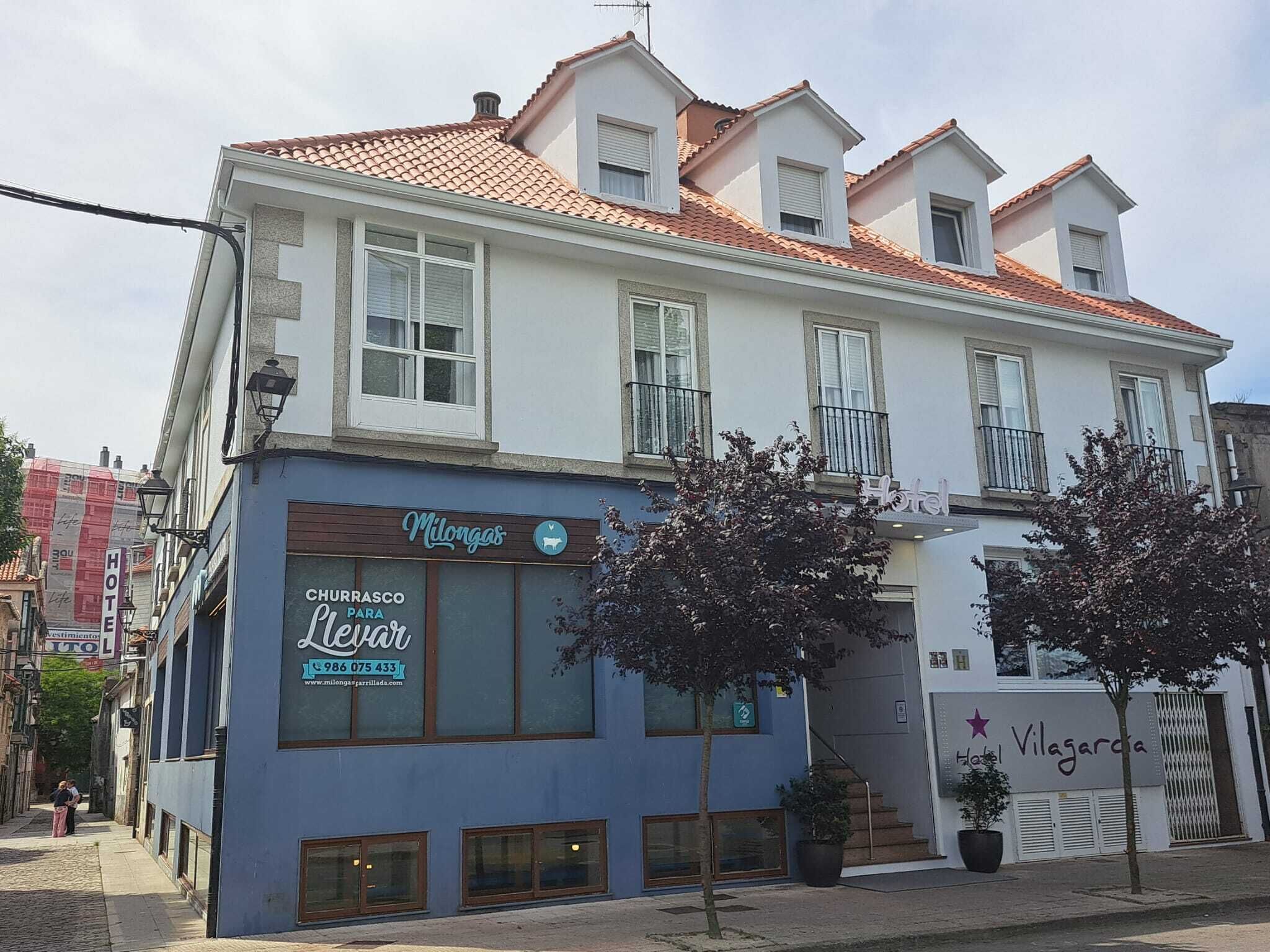 Um hotel com fachada azul, várias janelas e telhado de telhas vermelhas.
