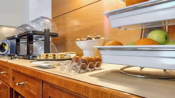 Um buffet de café da manhã com diversos alimentos e uma máquina de café.