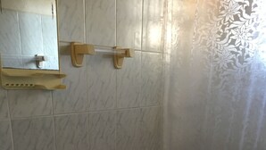 Casa de banho com lavatório branco, sanita e espelho com porta-toalhas em cima.