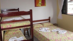 Quarto com beliche, cama de solteiro e uma pequena mesa.
