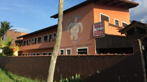 Edifício com um mural de um personagem e uma placa indicando "Aluga-se Suites".
