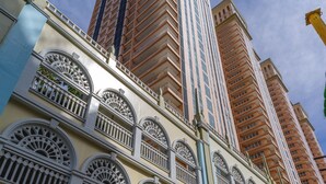 Um edifício de vários andares com estilo arquitetônico tradicional, apresentando varandas ornamentadas e uma placa indicando uma saída.