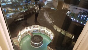 Hotel alto com um pátio central que apresenta uma fonte circular, várias varandas e vista para o horizonte urbano.