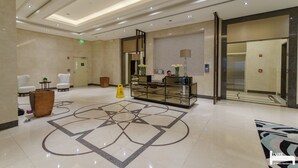 Um hall amplo com design moderno, incluindo uma receção, área de estar e um elevador.