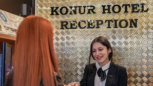 Uma área de recepção com parede estampada e o texto "KONUR HOTEL RECEPTION".