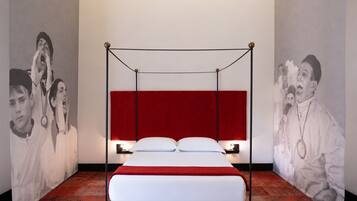 Uma cama com cabeceira vermelha, roupa de cama branca e tapete vermelho.