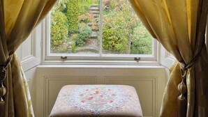 Quarto com janela, cortinas e cama com colcha florida.