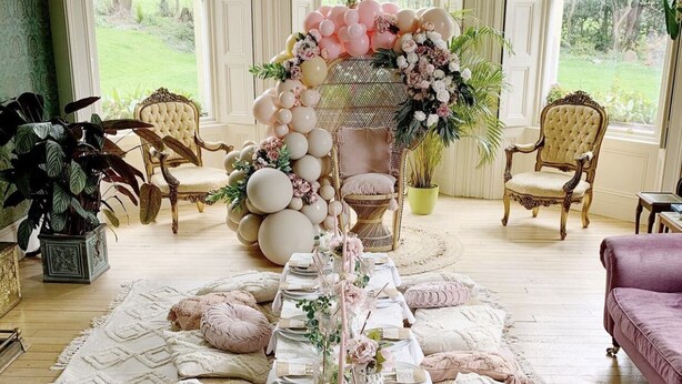 Um quarto com uma mesa comprida posta para refeição, rodeada por assentos confortáveis e um arranjo floral decorativo.