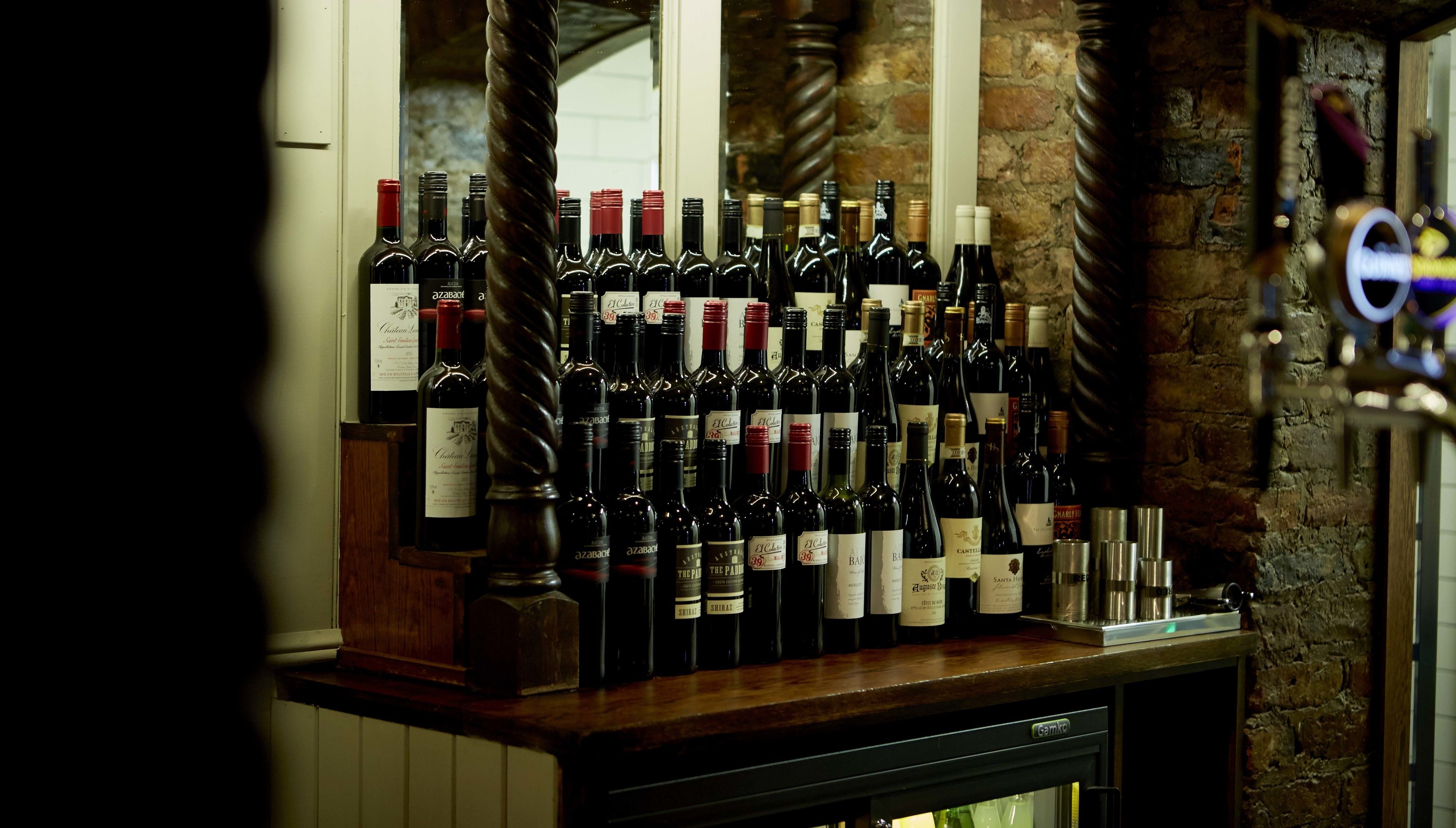 Uma área de bar com diversas garrafas de vinho expostas em prateleiras.
