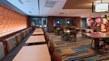 Um restaurante moderno com mesas comunitárias longas, cabines e um tapete estampado.