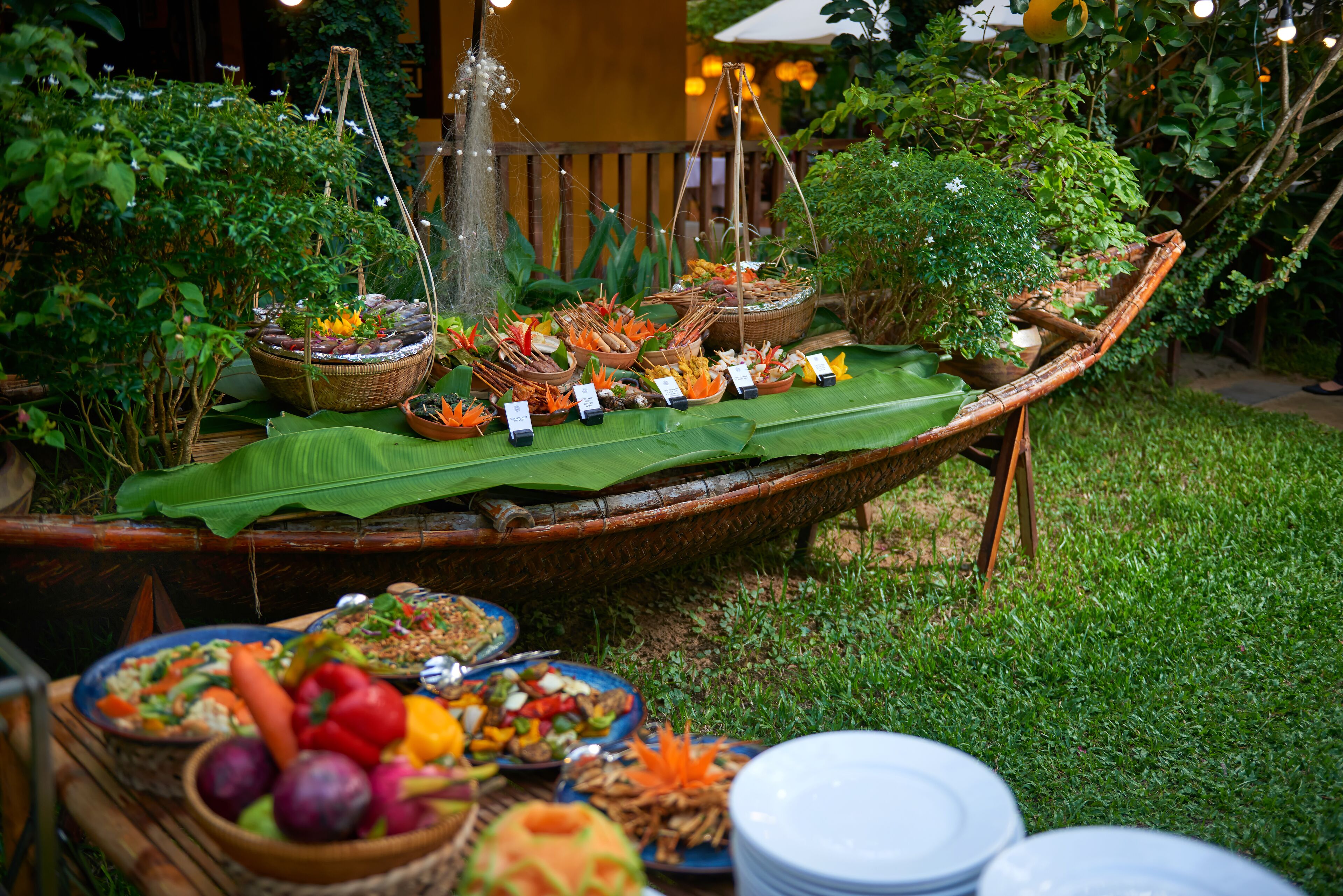 Um barco cheio de diversos alimentos e cestas, rodeado por vegetação e um jardim.