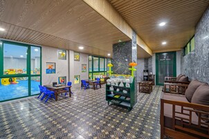 Espaço infantil com piscina, cadeiras azuis e uma mesa cheia de brinquedos.