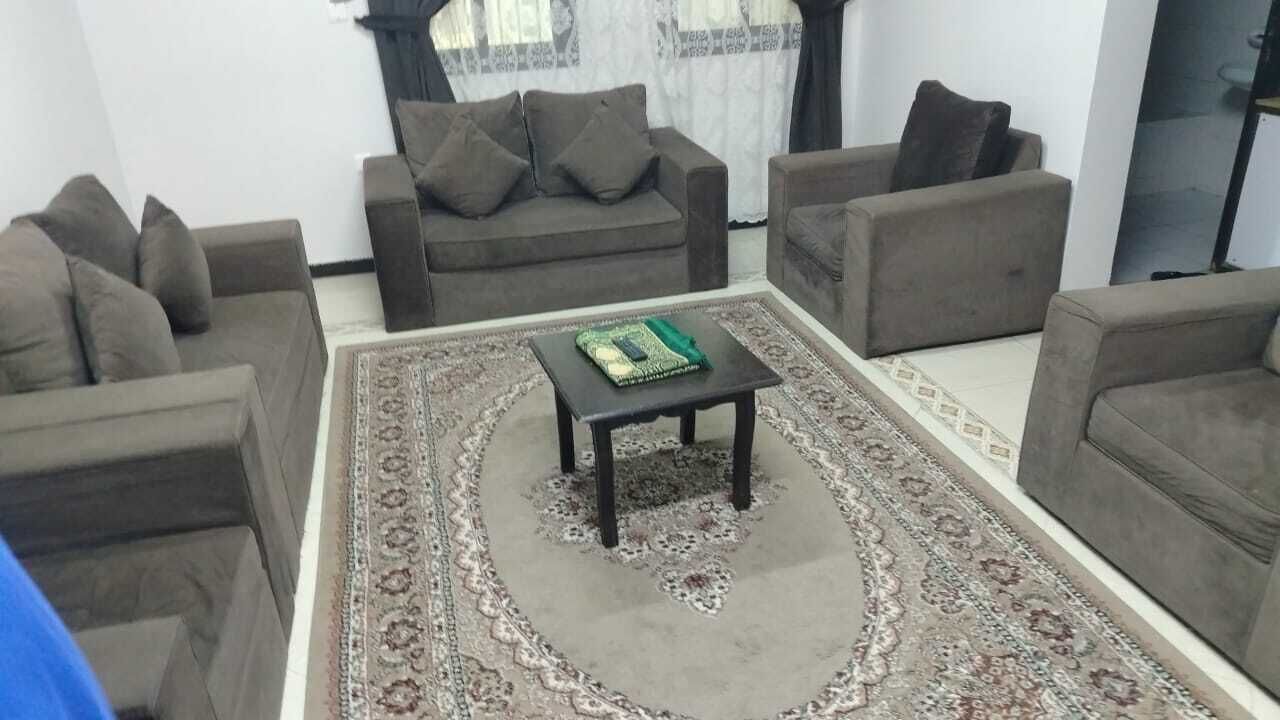 Sala de estar com sofá cinza, mesa de centro e tapete estampado.
