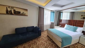 Quarto de hotel com cama, sofá, mesa de cabeceira, telefone e espelho.
