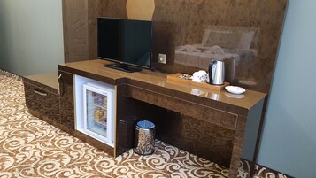 Quarto de hotel com televisão de tela plana, minibar, cafeteira e lixeira.